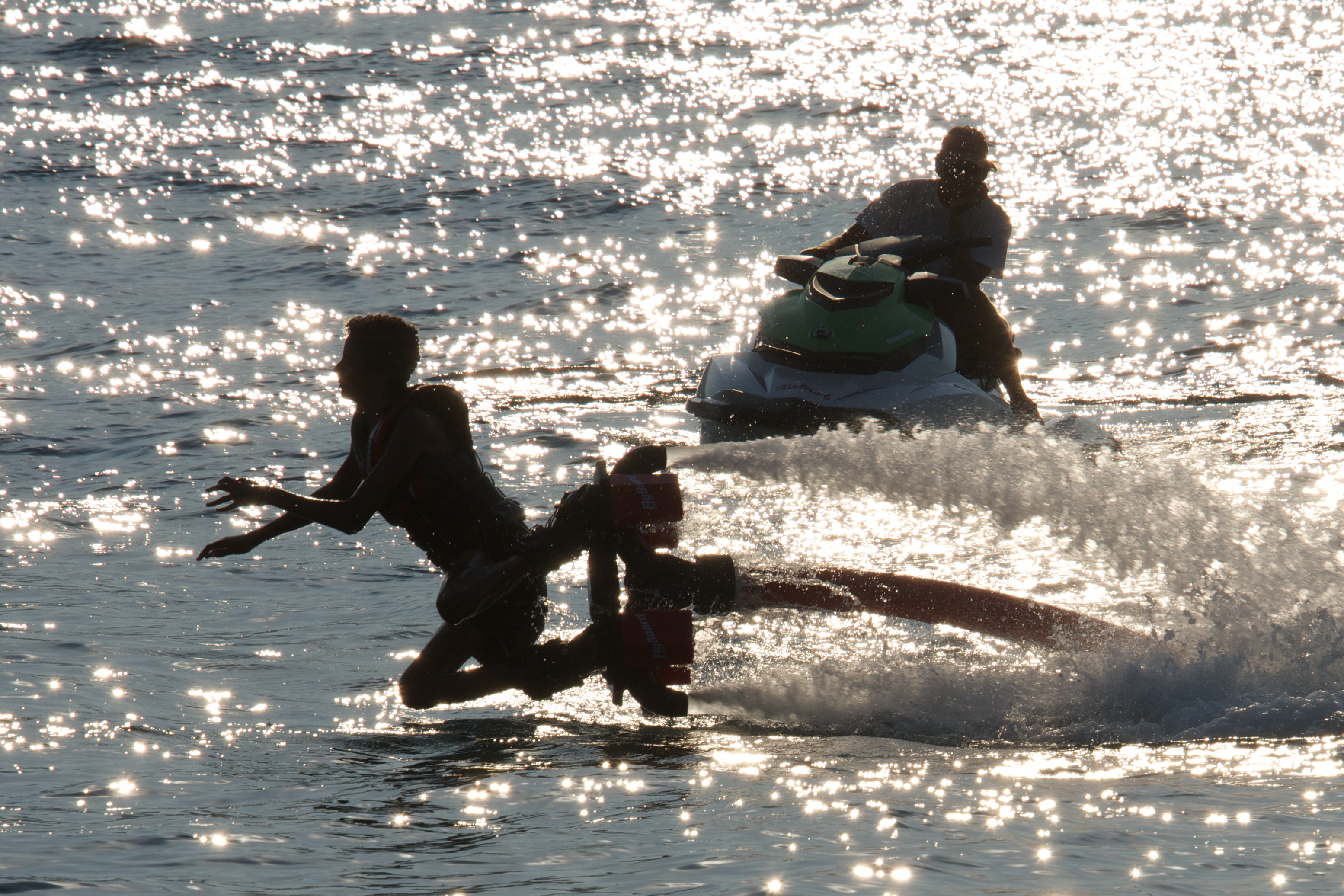 Flyboarder falling forwards beside backlit Jet Ski - Nick Dale ...