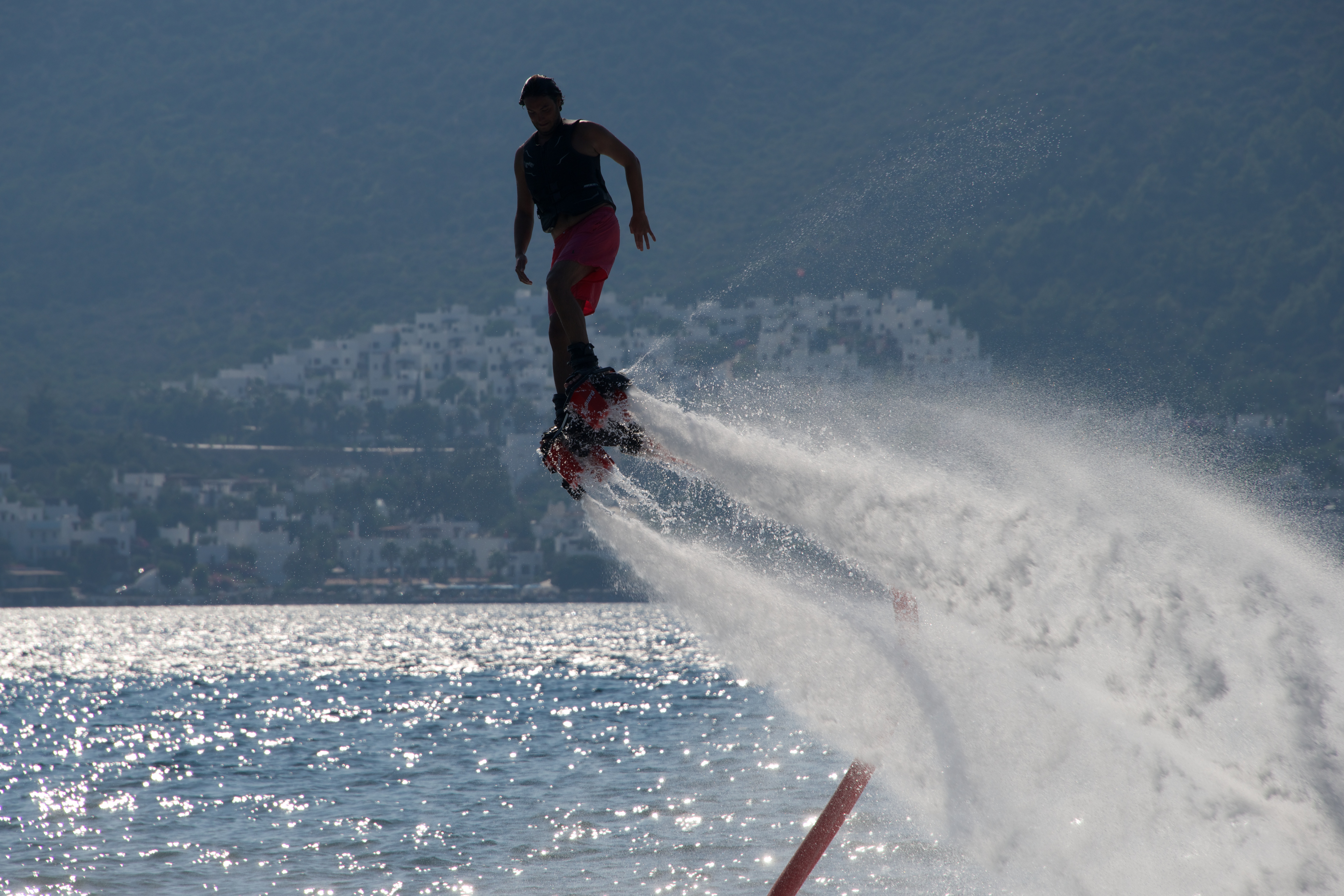 Flyboarder followed by spray over backlit sea | Nick Dale – Private Tutor