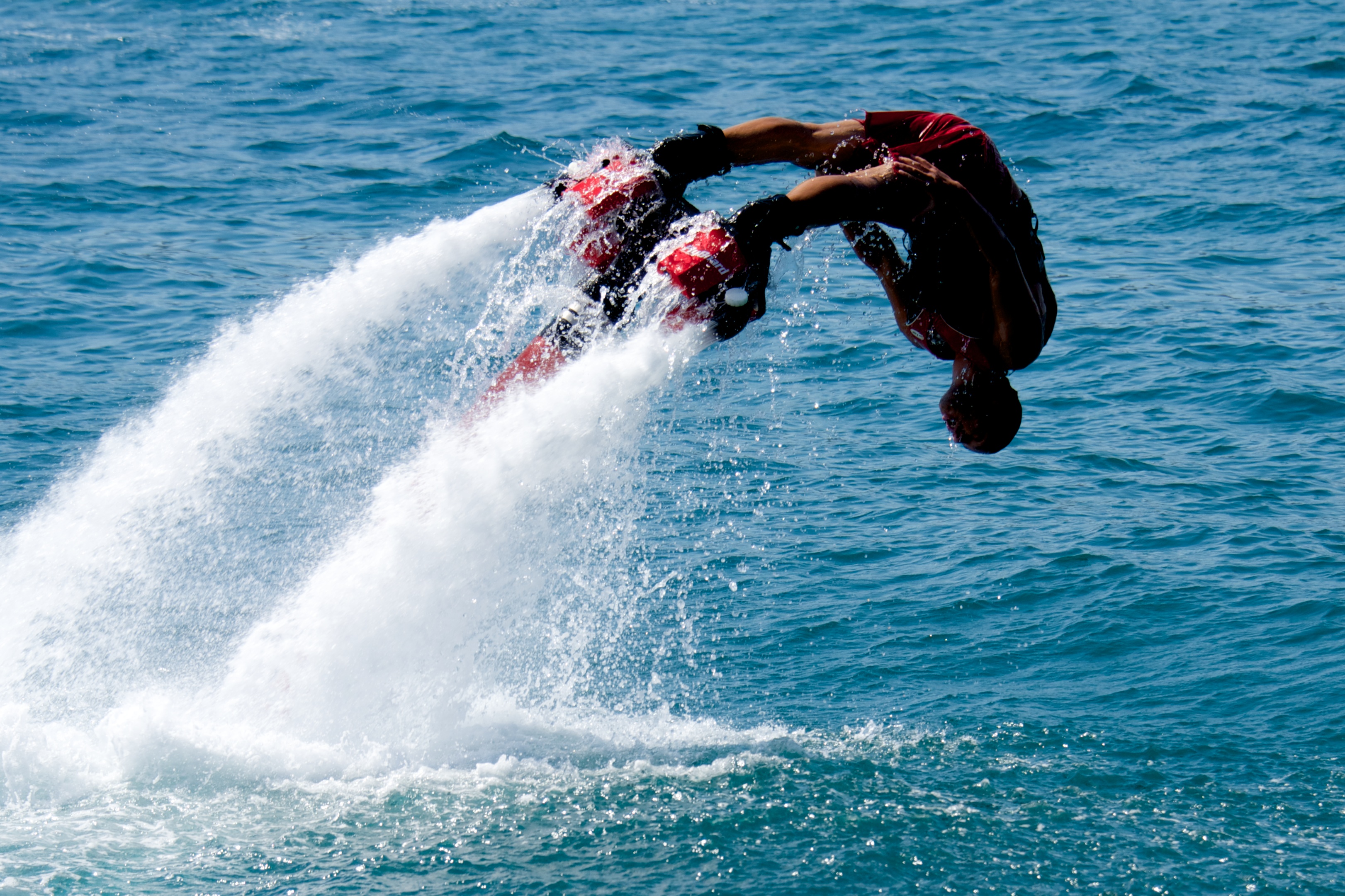 Flyboarder in red diving headfirst into water - Nick Dale - Private Tutor