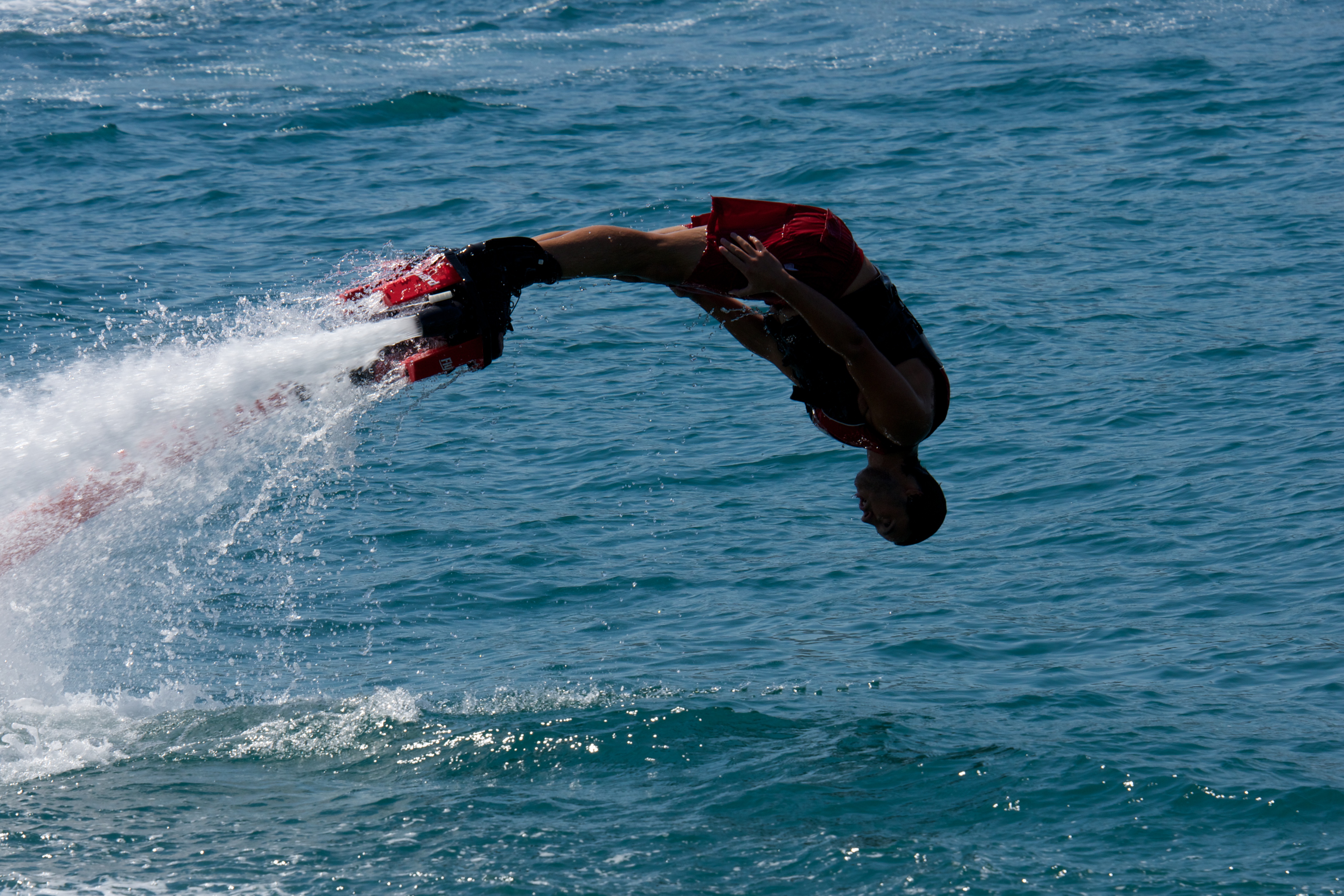 Flyboarder in silhouette diving headfirst into water - Nick Dale ...