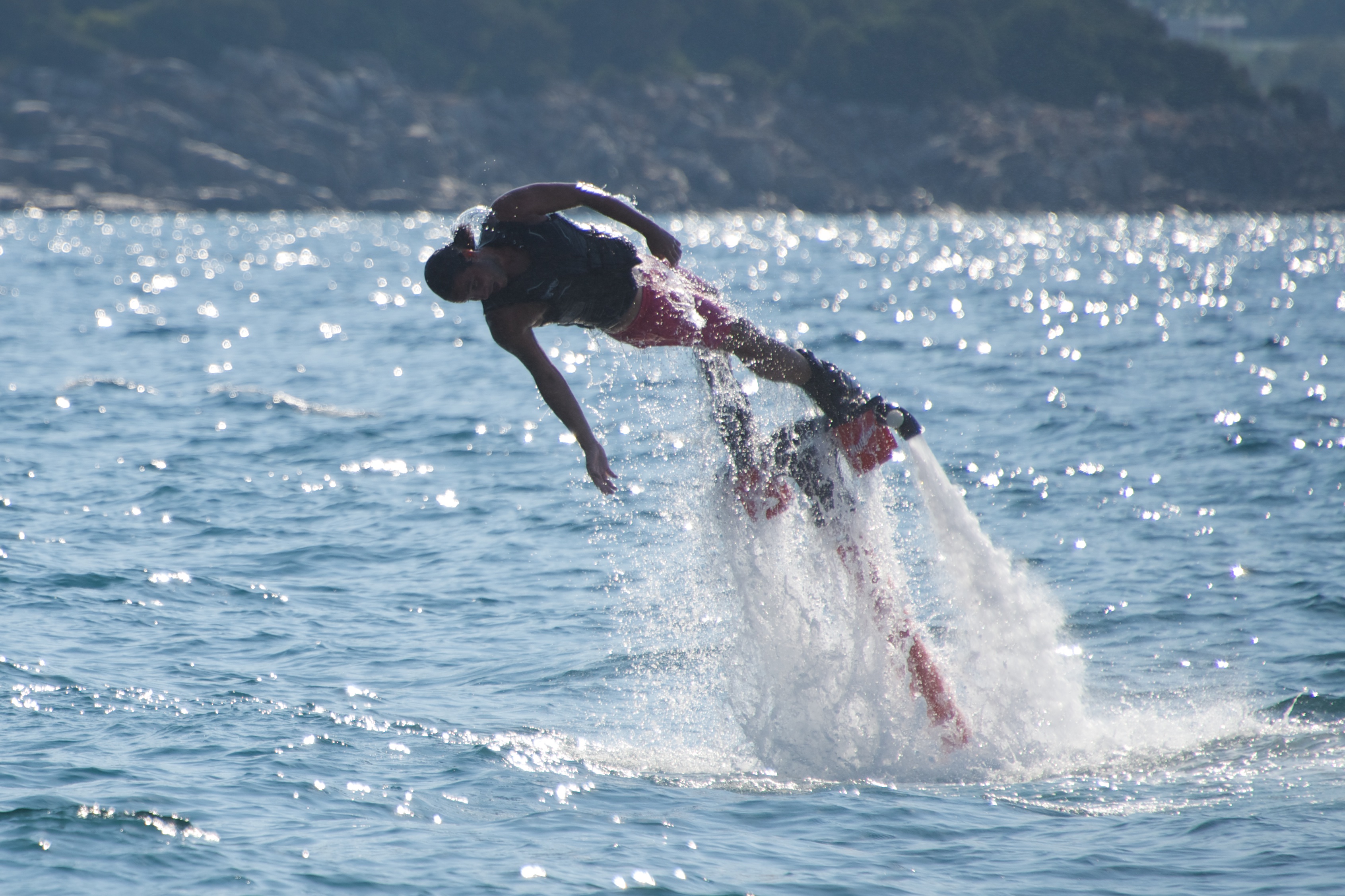 Flyboarder twisting to dive into backlit waves - Nick Dale - Private Tutor