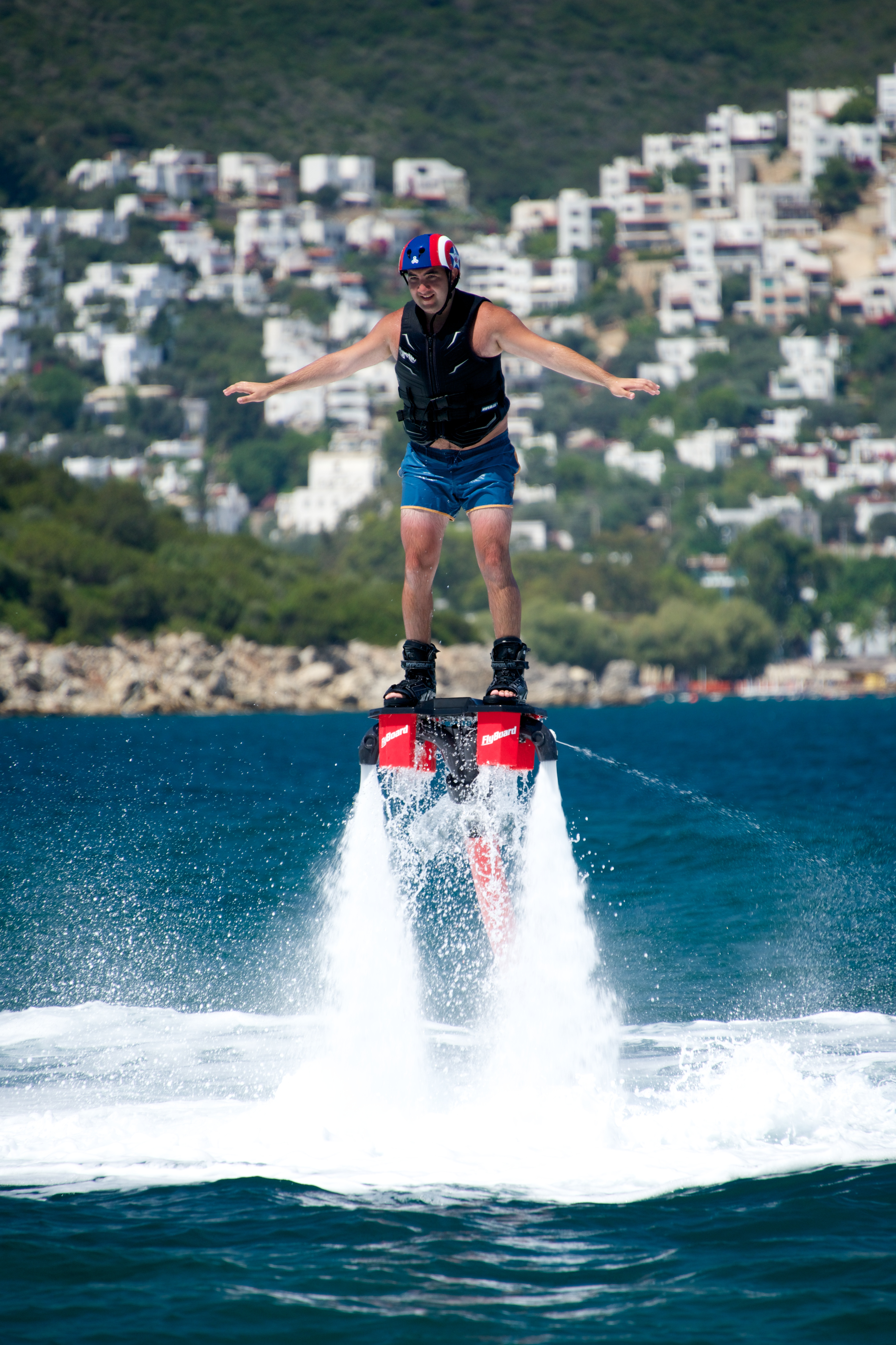 Flyboarder with arms out and village behind | Nick Dale – Private Tutor